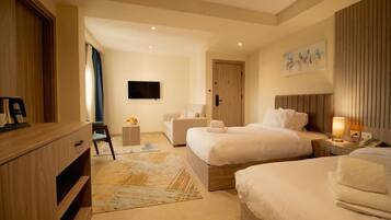 Quarto de hotel com duas camas, televisão, escrivaninha e uma cadeira.
