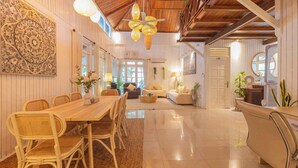 Um quarto espaçoso com uma mesa de jantar de madeira, cadeiras de vime, um sofá e uma banheira.