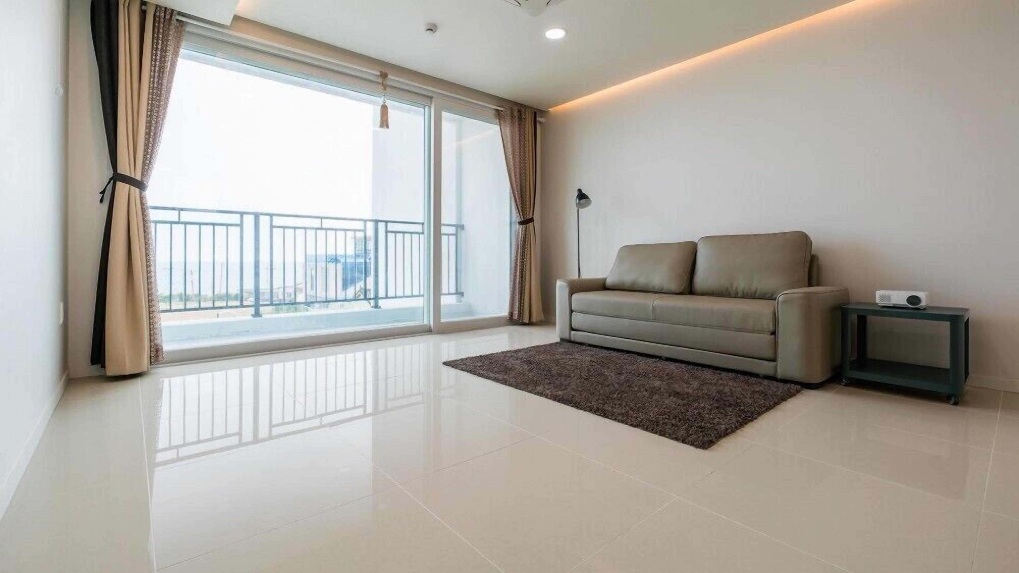 Uma sala de estar moderna com sofá, uma mesinha e uma janela grande com cortinas.