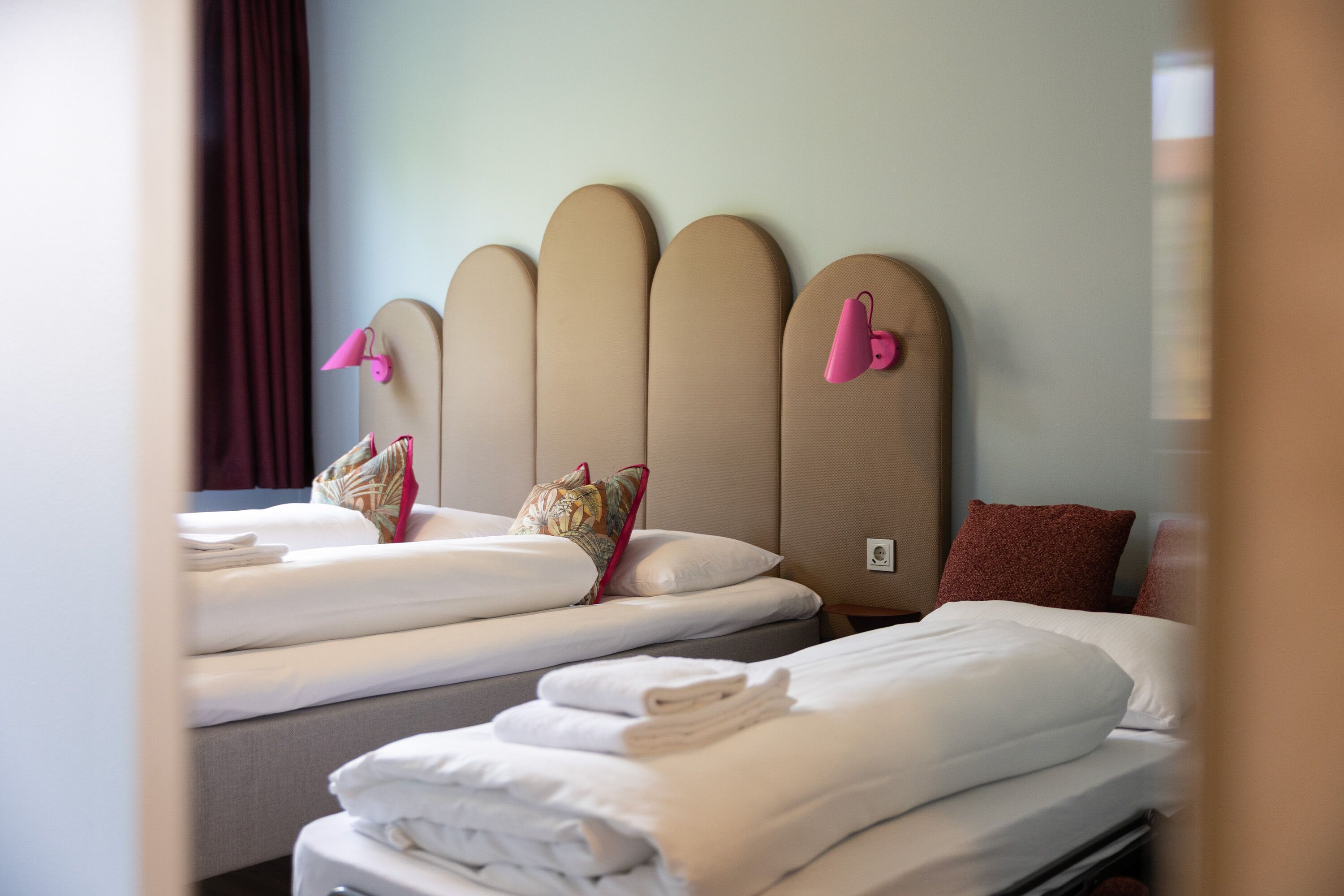 Quarto de hotel com duas camas, cada uma com roupa de cama branca e impecável e almofadas.