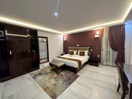 Quarto de hotel com cama, escrivaninha, guarda-roupa e banheiro.