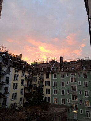 Uma fileira de edifícios residenciais com varandas e um céu ao pôr do sol.
