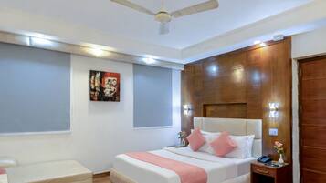 Quarto com cama, mesa de cabeceira e ventoinha no teto.