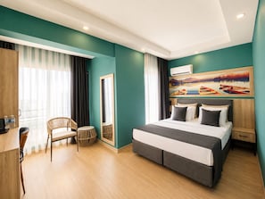 Quarto de hotel moderno com uma cama grande, uma escrivaninha, uma cadeira e um quadro na parede.
