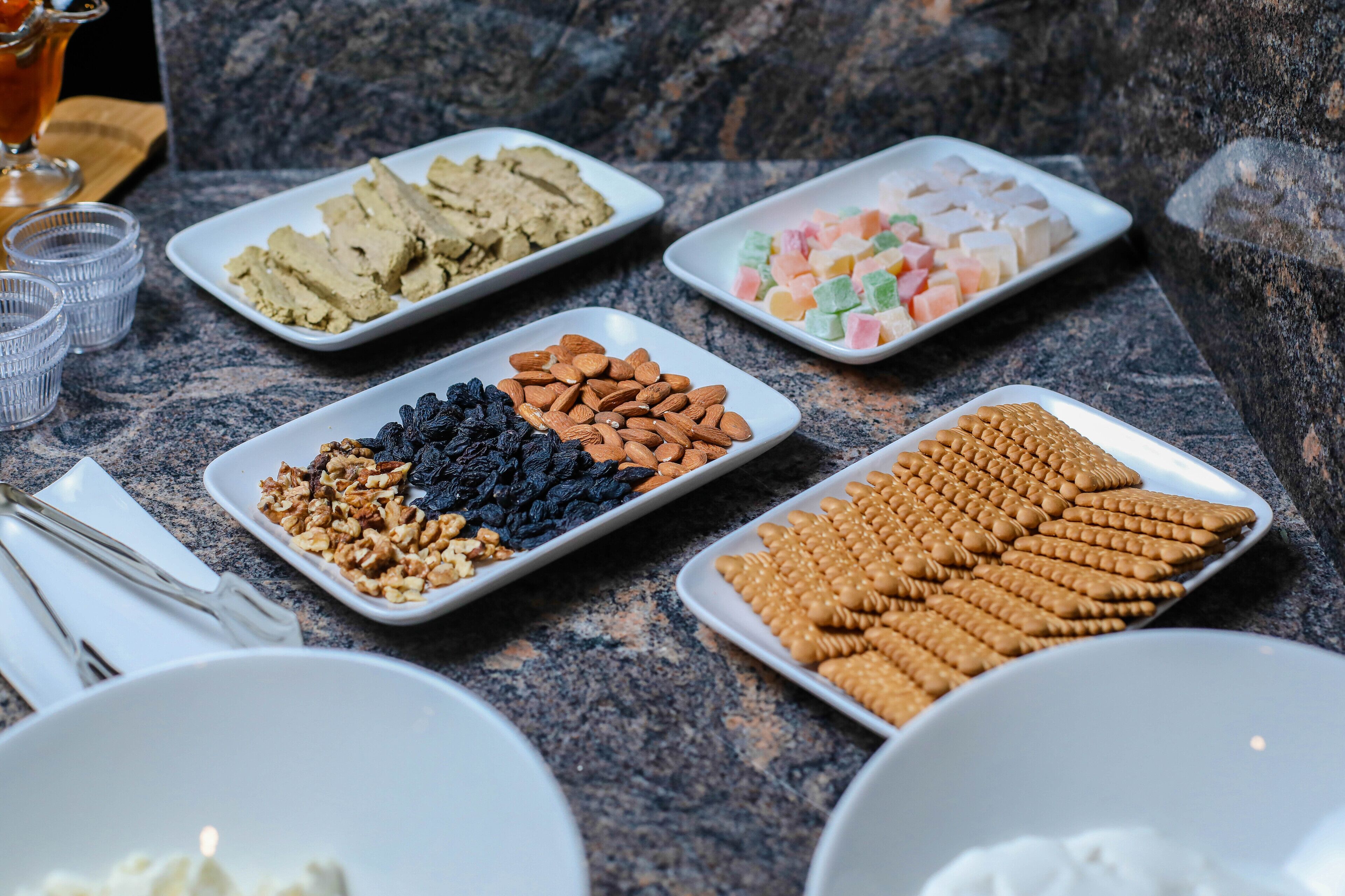 Uma mesa de buffet com diversos alimentos, incluindo frutos secos, frutas cristalizadas e doces.