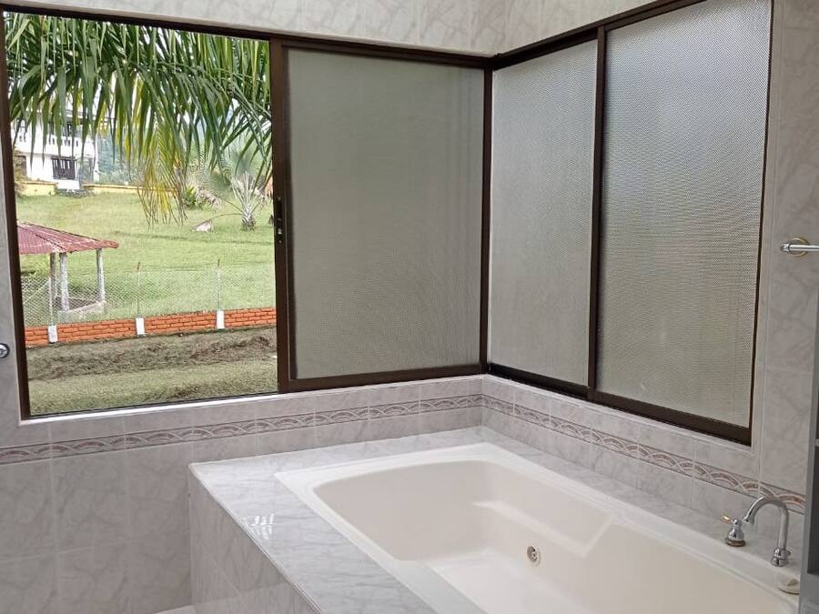 Casa de banho com uma banheira grande, portas de vidro jateado e vista para um jardim.
