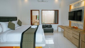 Quarto de hotel moderno com uma cama grande, um sofá, uma TV e um armário de madeira.