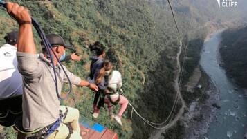 Uma pessoa faz bungee jump com um instrutor segurando um arnês de segurança.