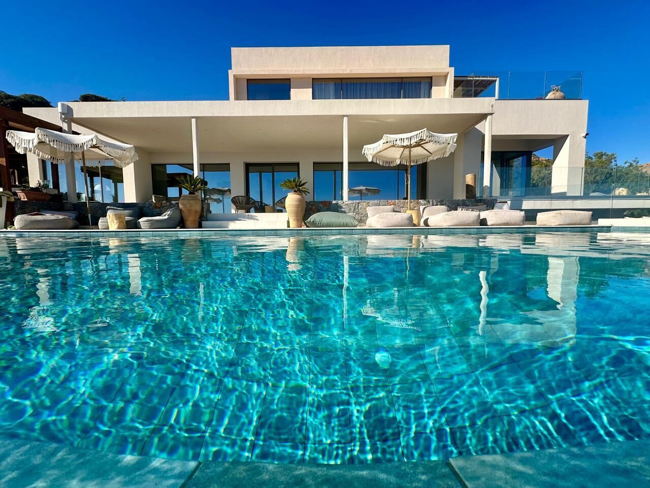 Um hotel moderno com piscina, área de estar externa e céu azul.