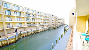 Um hotel com vários andares, varandas, um canal e um cais.