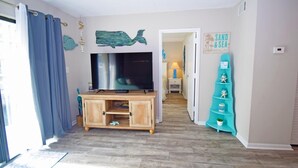 Uma sala de estar com um aparador de madeira, uma TV de tela plana e uma prateleira decorativa azul-esverdeada.