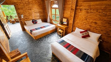 Uma cabana de madeira com duas camas, uma escrivaninha pequena e uma janela com cortinas.