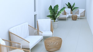 Uma área de estar moderna e minimalista, com sofás brancos, mobiliário de vime e plantas em vasos.