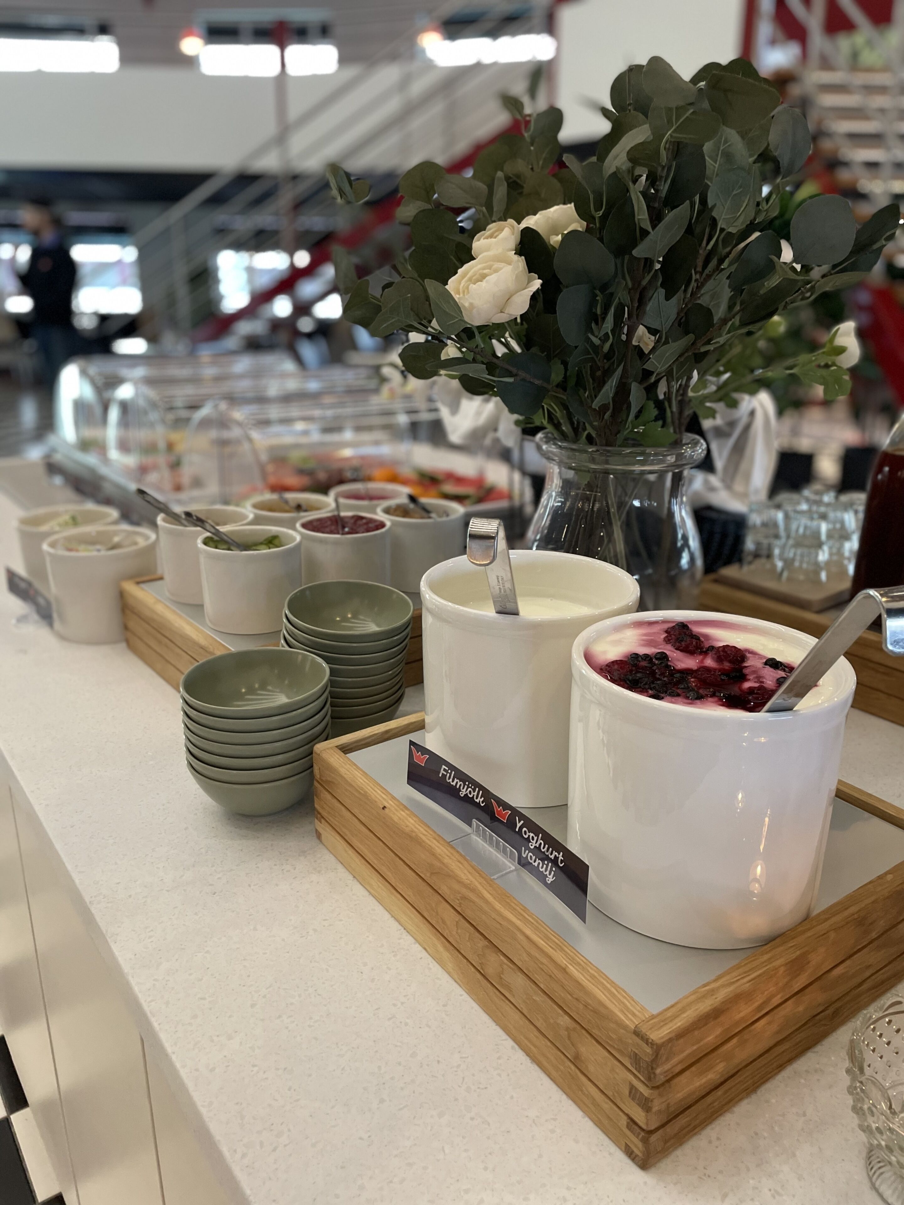 Uma área de buffet com diversos alimentos e um letreiro indicando 'Filmjölk Yogurt vanily'.