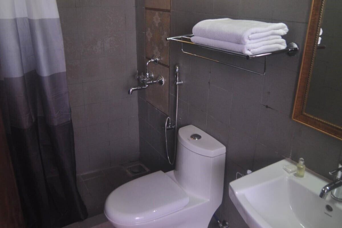 Casa de banho com sanita branca, lavatório e suporte para toalhas.