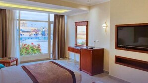 Quarto de hotel com cama, escrivaninha, televisão e vista para o exterior.