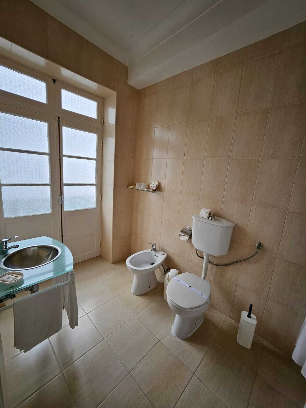 Uma casa de banho com lavatório de vidro, bidé, sanita e zona de duche.