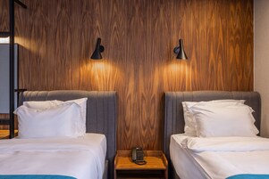 Quarto de hotel com duas camas, parede de madeira e mesa de cabeceira com telefone.