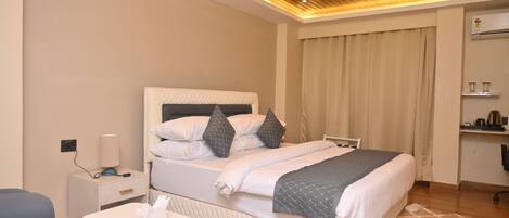Quarto de hotel com cama, mesa de cabeceira, luminária e ventilador de teto.