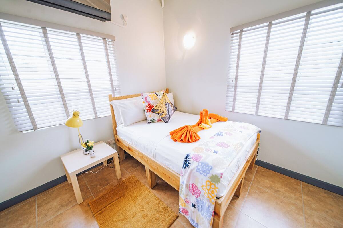 Quarto com cama, mesa de cabeceira e janela.