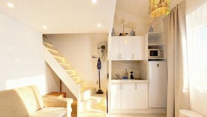 Um interior moderno com escada, cozinha compacta e área de estar.