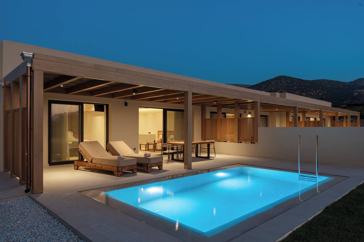 Uma área de piscina moderna ao ar livre, com espreguiçadeiras e um espaço de estar coberto.