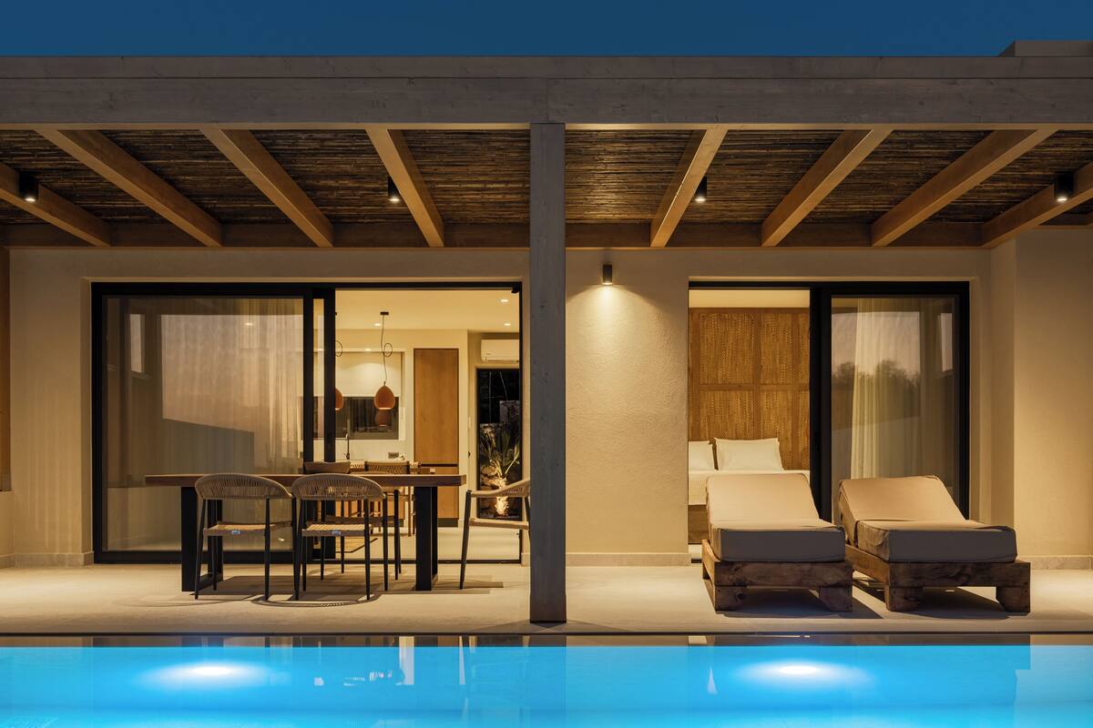Uma área moderna de piscina externa com mesa e cadeiras, um sofá e uma cama.