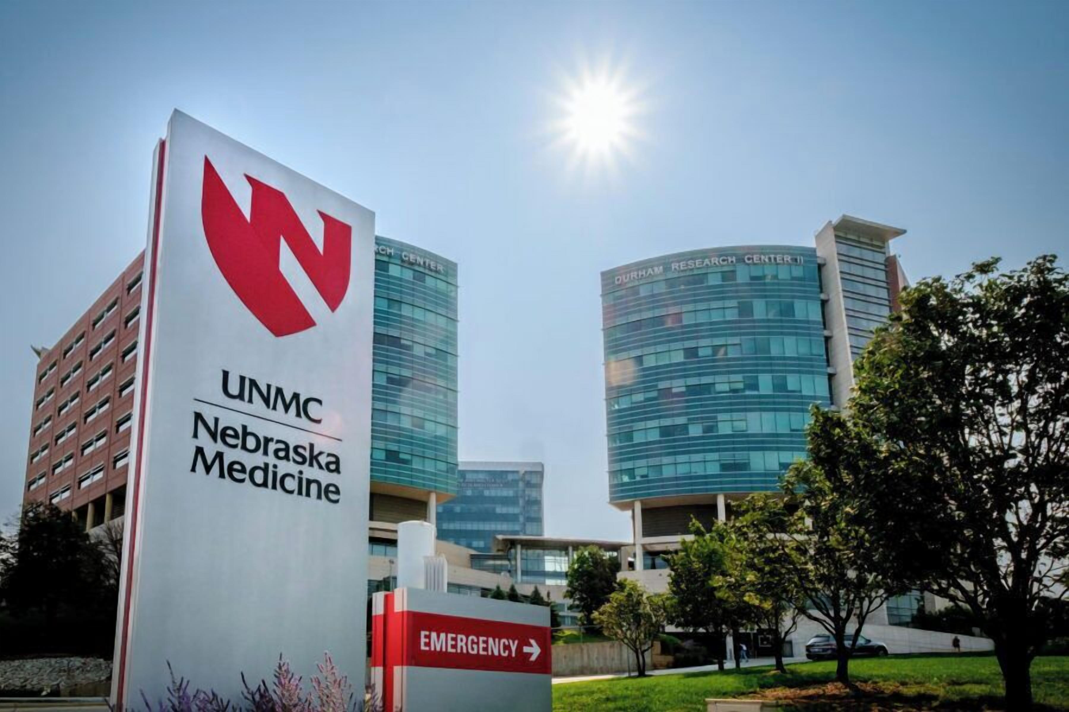 Edifício da UNMC Nebraska Medicine com placa de emergência, arquitetura moderna e céu claro.