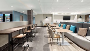 Um restaurante moderno com mesas comunitárias grandes e um espaço com sofás.