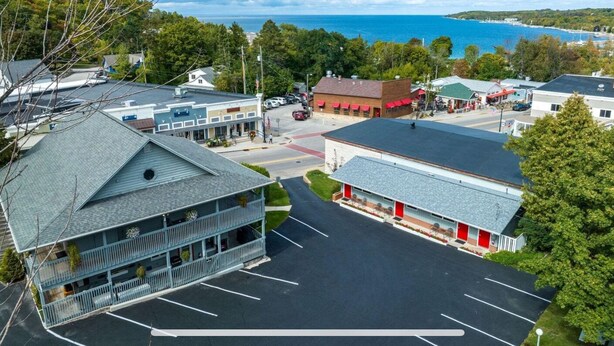 Uma cidade costeira com um estacionamento, um edifício com toldo vermelho e vista para o oceano.