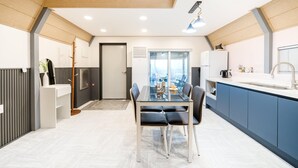 Cozinha moderna com área de refeições, destacando uma mesa de vidro, armários azuis e vista para a cidade.