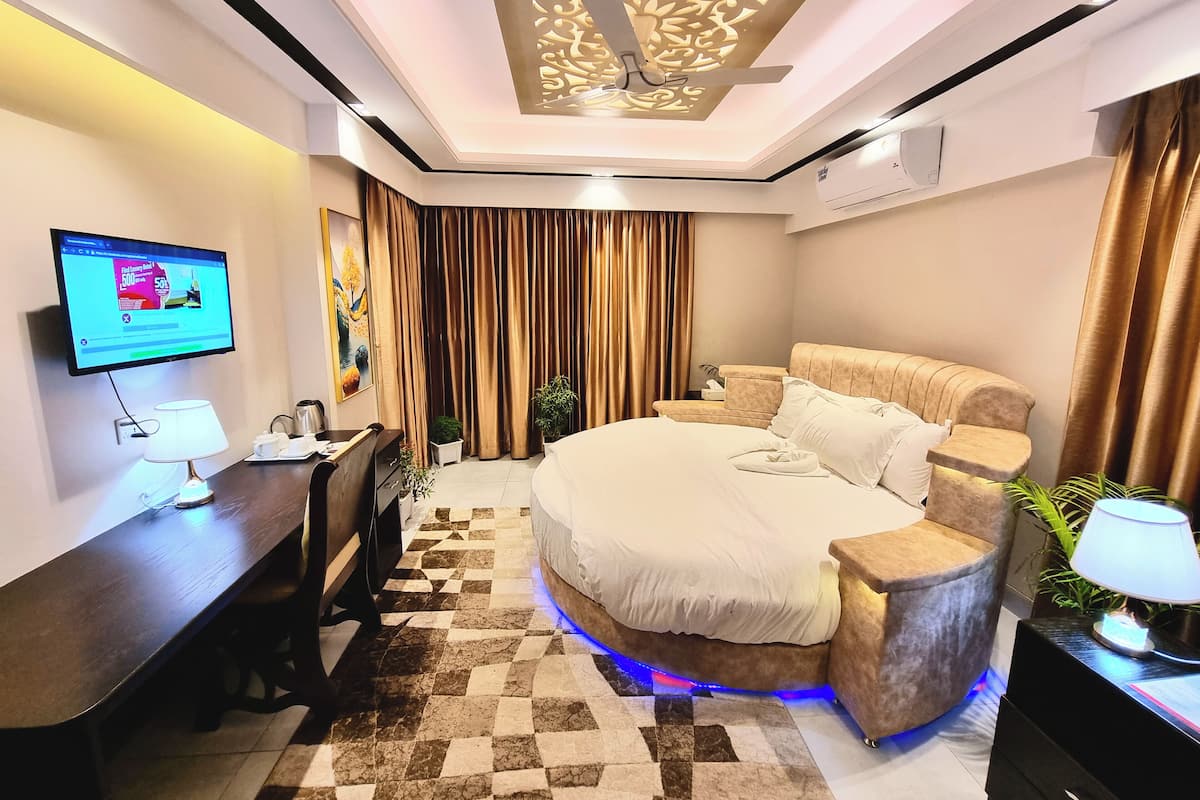 Quarto de hotel moderno com uma cama grande, uma escrivaninha, uma televisão e um candeeiro de teto.