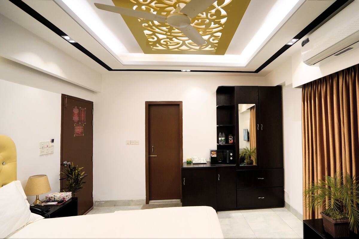Quarto moderno com cama, escrivaninha, guarda-roupa e ventoinha no teto.