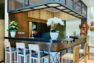 Uma área de recepção com balcão, cadeiras e plantas decorativas.