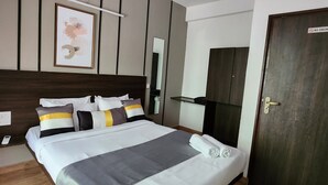 Quarto de hotel com uma cama grande, uma mesa de cabeceira, um espelho e um guarda-roupa.