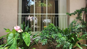 Uma varanda com guarda-corrimão branco, luminária pendente e plantas verdes exuberantes.