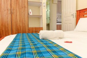 Quarto de hotel com colcha xadrez, guarda-roupa de madeira e porta branca.