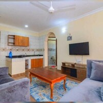 Uma sala de estar com mesa de centro de madeira, um sofá e uma televisão na parede.