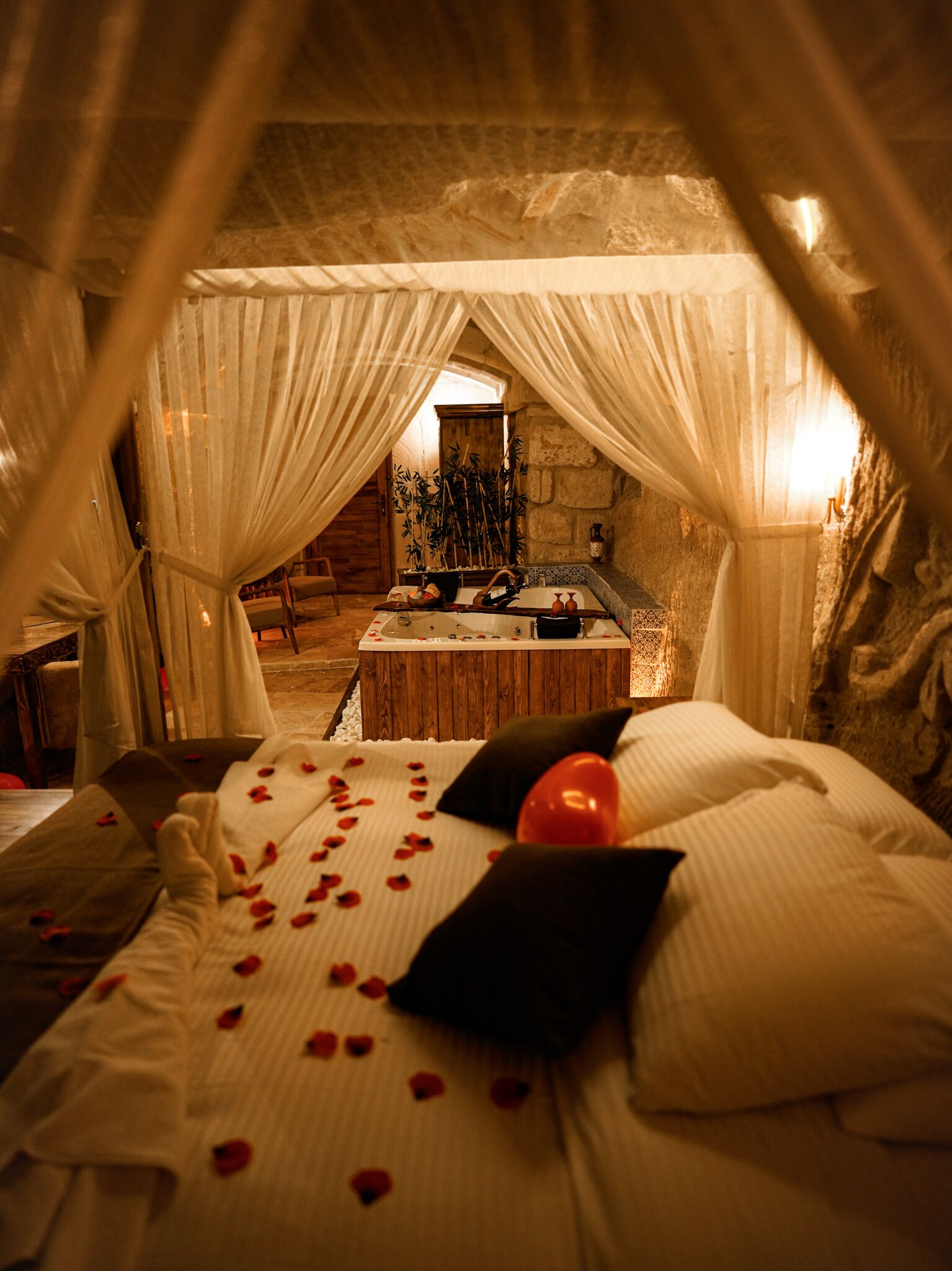 Um quarto aconchegante com cama, almofadas e pétalas de rosa.