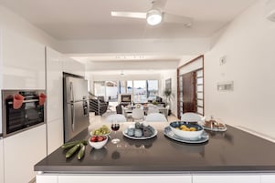 Cozinha moderna com ilha central, eletrodomésticos de aço inoxidável e vista para a sala de jantar.