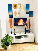 Sala de estar com televisão, pratos decorativos e uma planta em vaso.