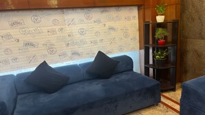 Um sofá azul com almofadas pretas, um armário de madeira e uma parede com selos postais aéreos.