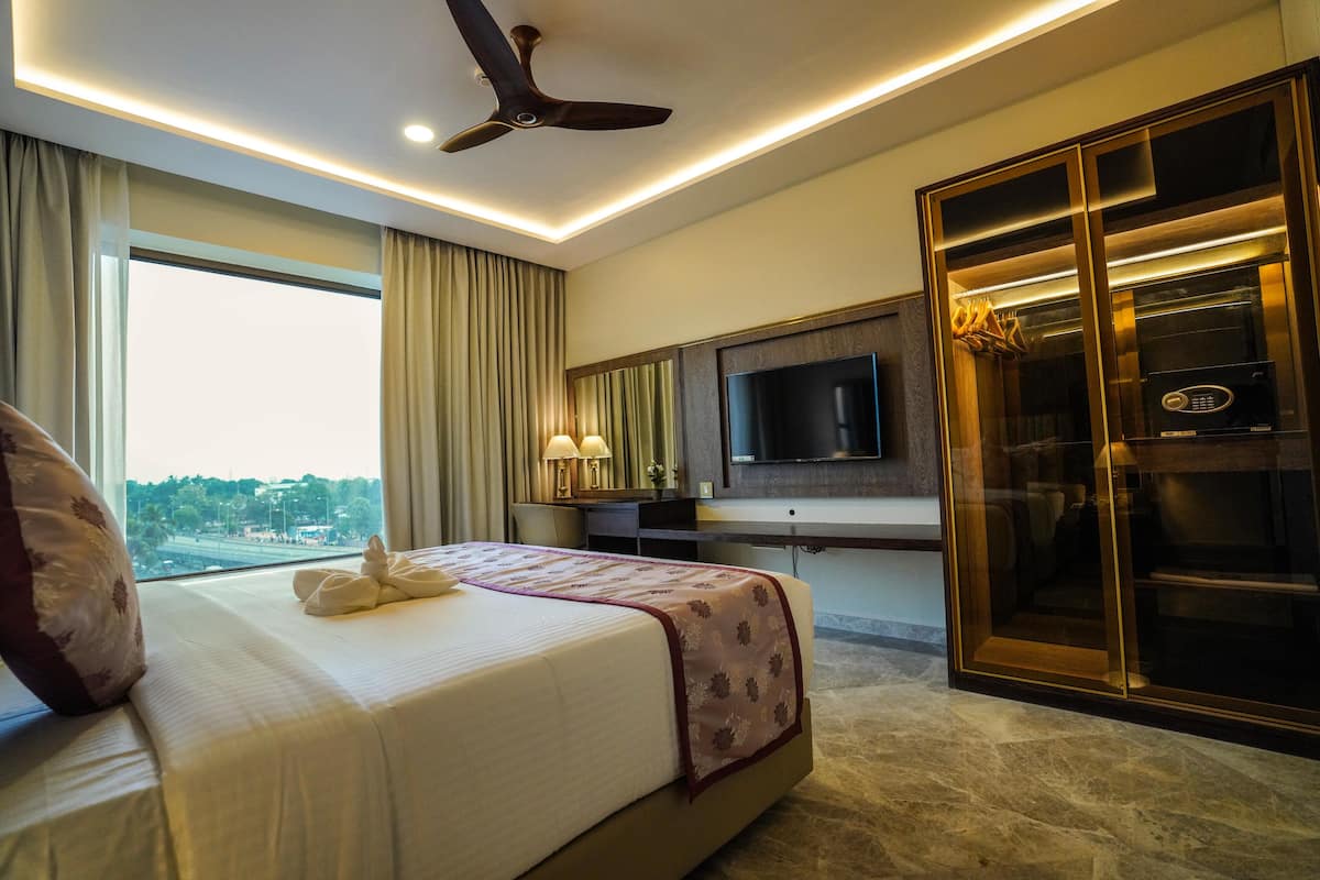 Quarto de hotel com cama, secretária, televisão e guarda-roupa.