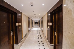 Corredor comprido e estreito com portas numeradas, que dá acesso a quartos.
