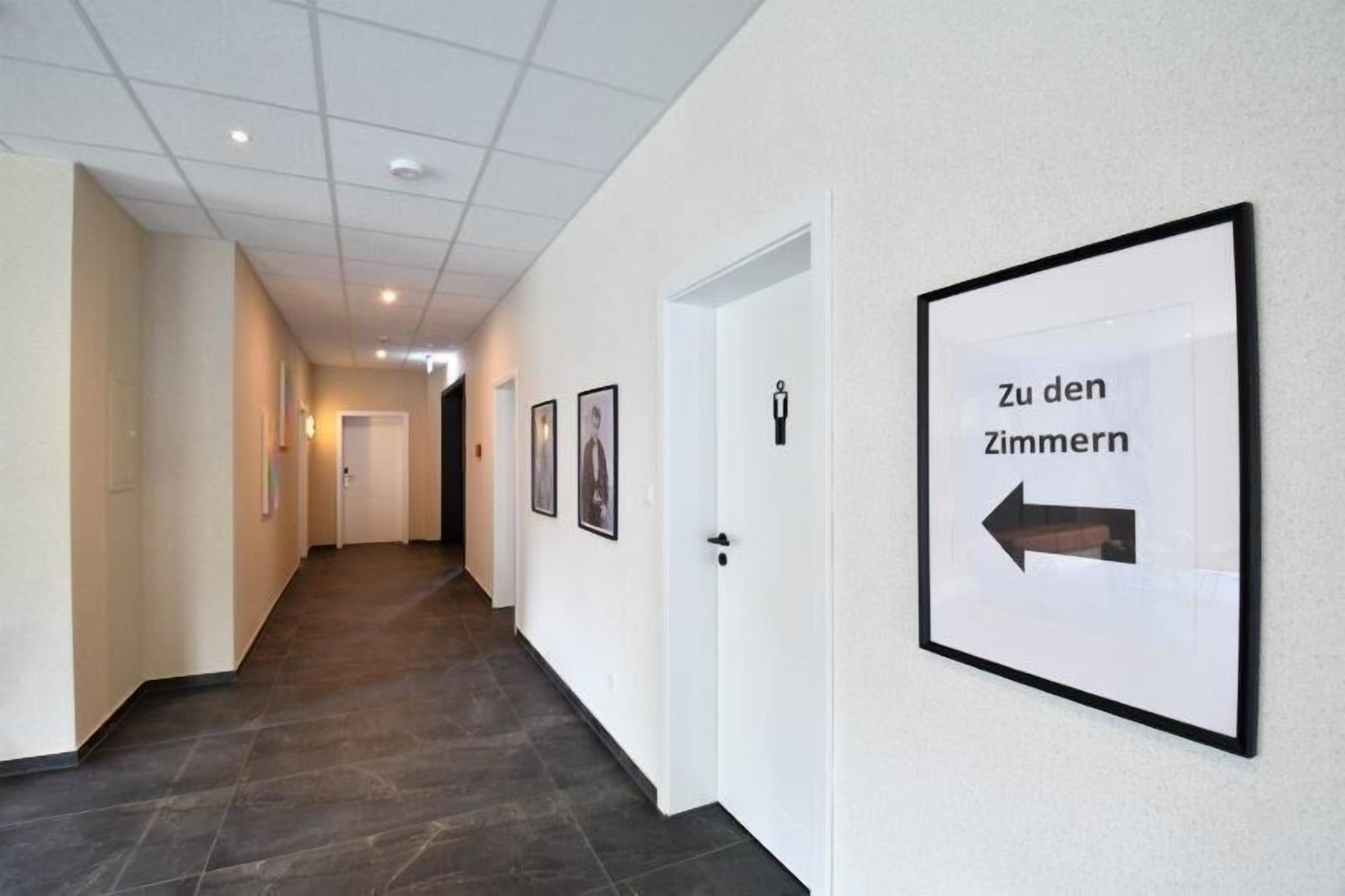 Um corredor com uma placa apontando para a direita, indicando o caminho para os quartos.