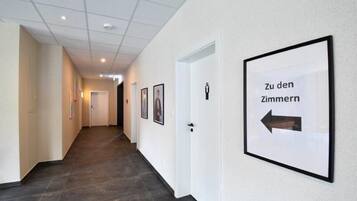 Um corredor com uma placa apontando para a direita, indicando o caminho para os quartos.