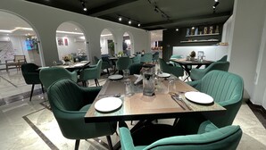 Uma sala de jantar moderna com cadeiras estofadas em verde e mesas, com um design limpo e contemporâneo e uma paleta de cores neutras.