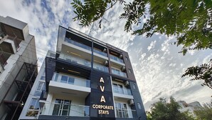 Um edifício com vários andares, varandas e uma placa com a inscrição 'AVA CORPORATE STAYS'.