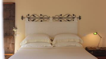Uma cama com cabeceira de metal, uma luminária de cabeceira e uma porta de madeira ao fundo.