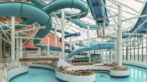 Parque aquático interno com vários toboáguas e uma área de piscina central.